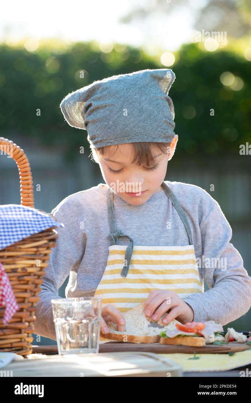 Boy making a sandwich wearing a triangular hood Stock Photo - Alamy