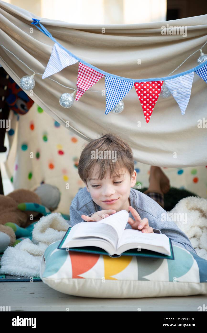 A boy reading a book in a tent made of sheets Stock Photo - Alamy