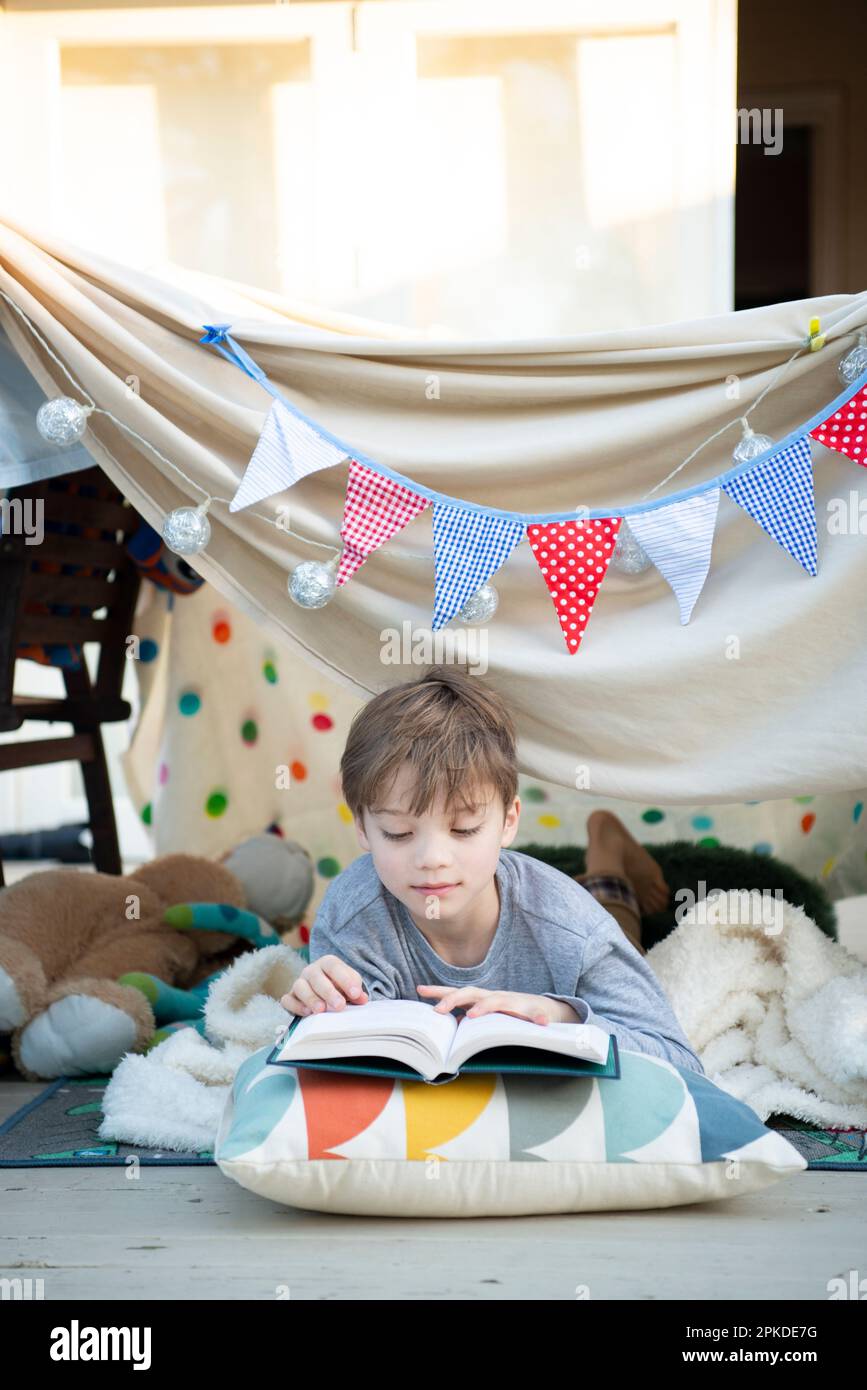 Boy reading a book in a tent made of sheets Stock Photo - Alamy