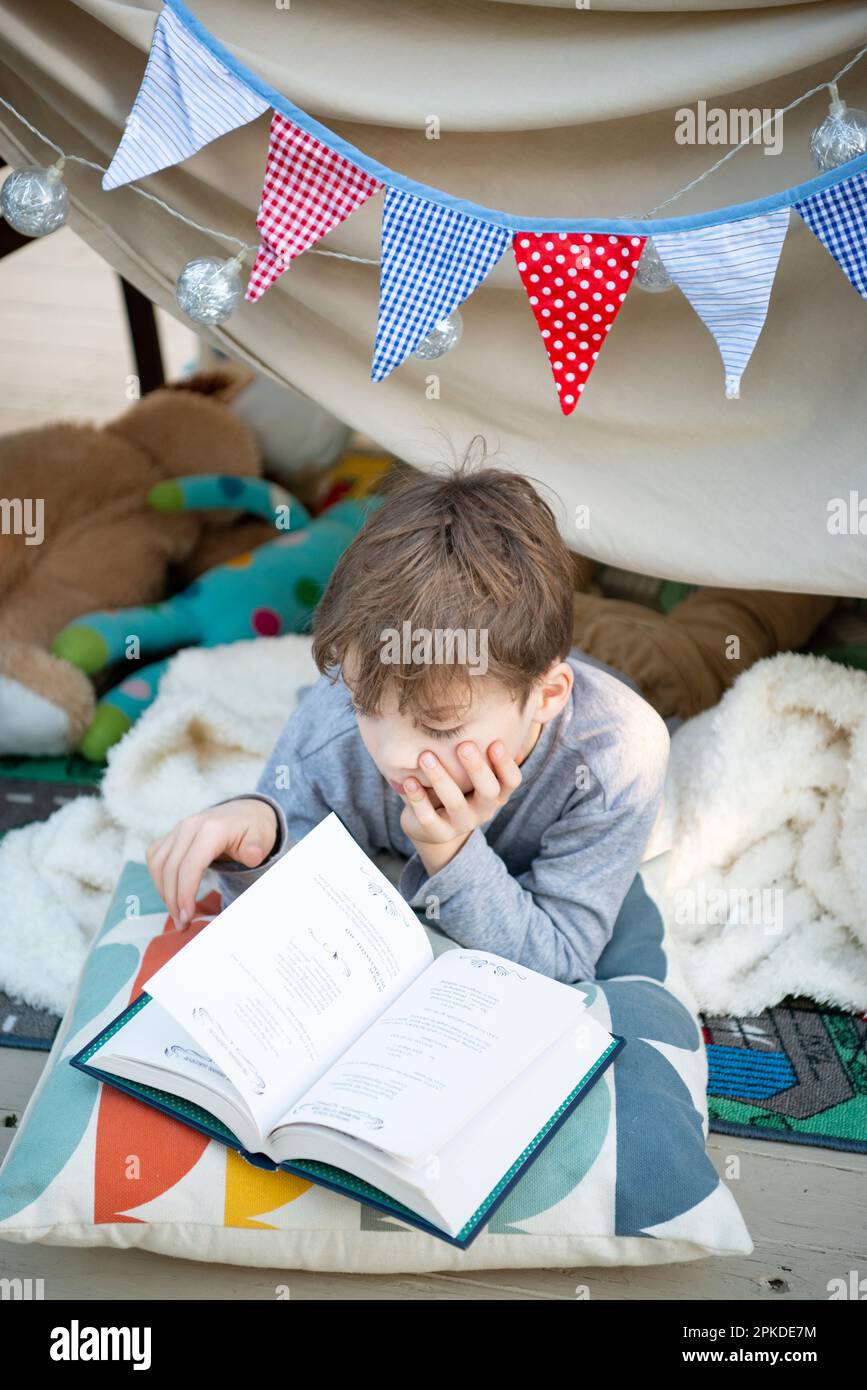 A boy reading a book in a tent made of sheets Stock Photo - Alamy
