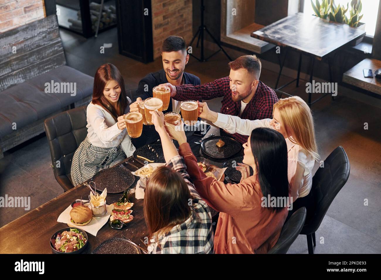 Delicious food. Group of young friends sitting together in bar with ...