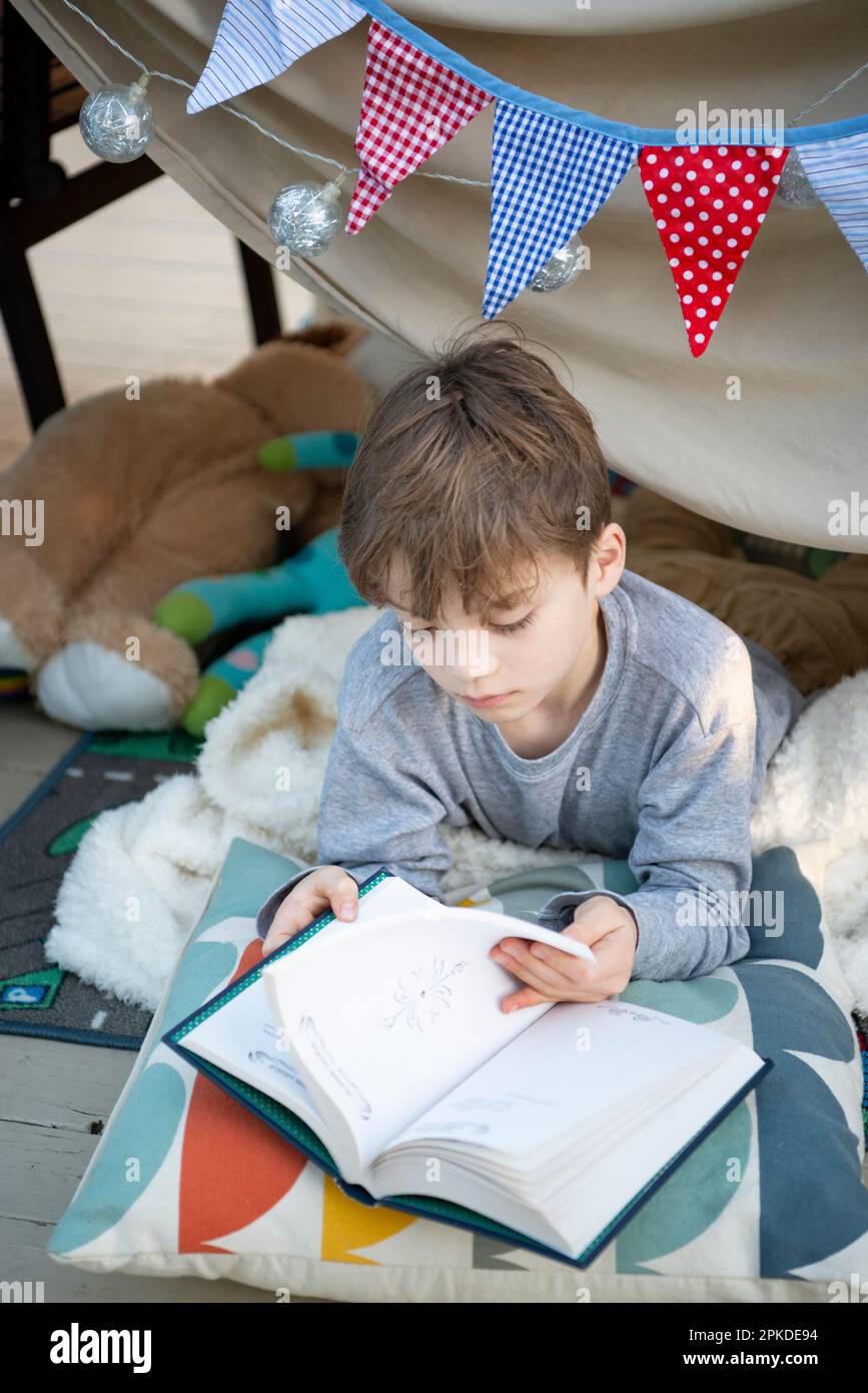 A boy reading a book in a tent made of sheets Stock Photo - Alamy