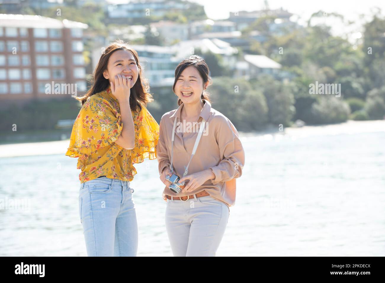 2 women laughing on the beach Stock Photo - Alamy