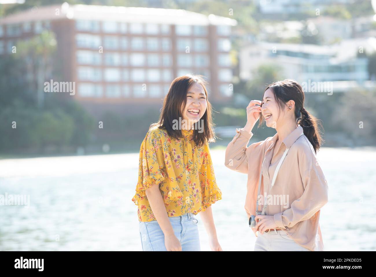 2 women laughing on the beach Stock Photo - Alamy