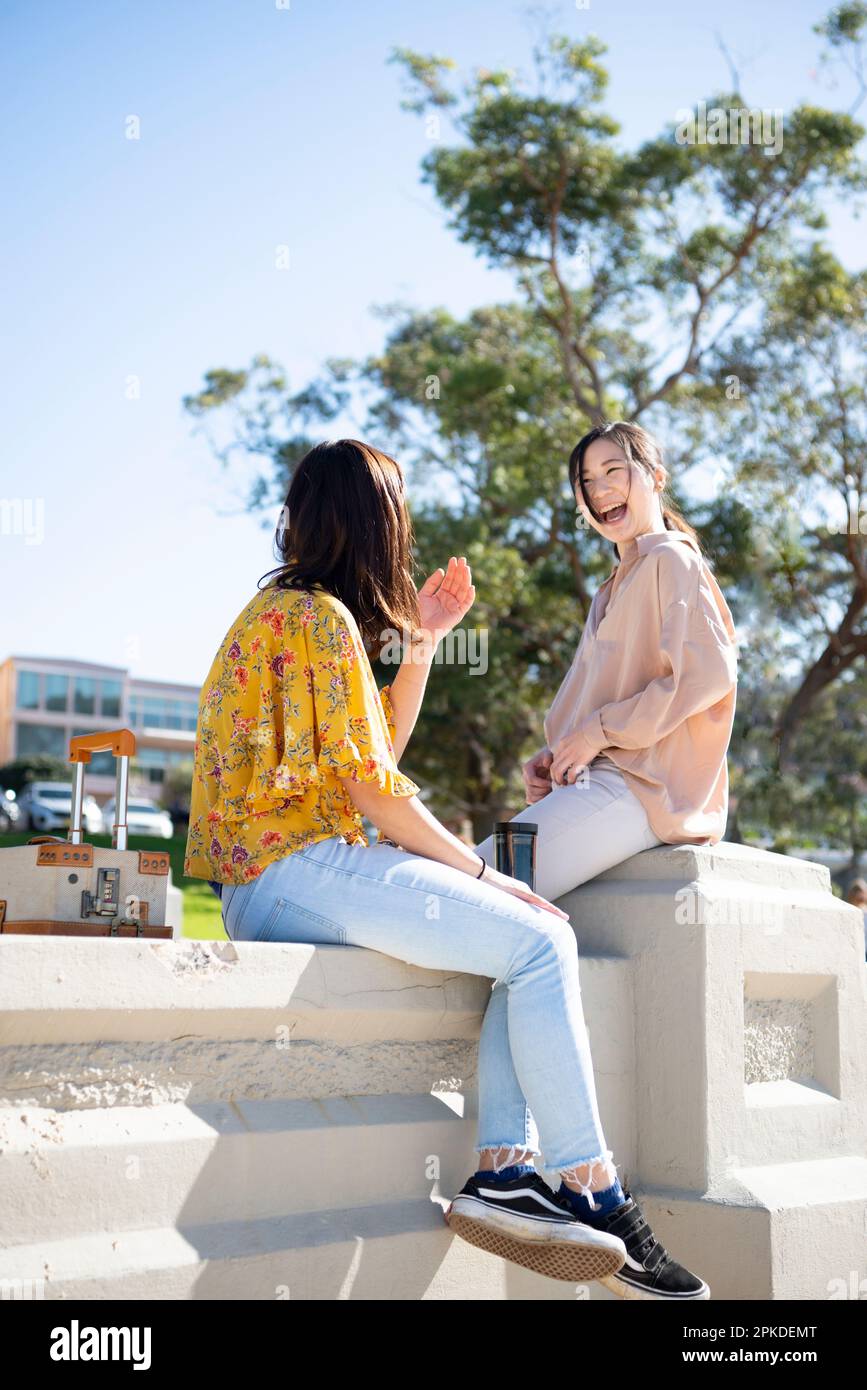 Two women sitting and talking and laughing Stock Photo - Alamy