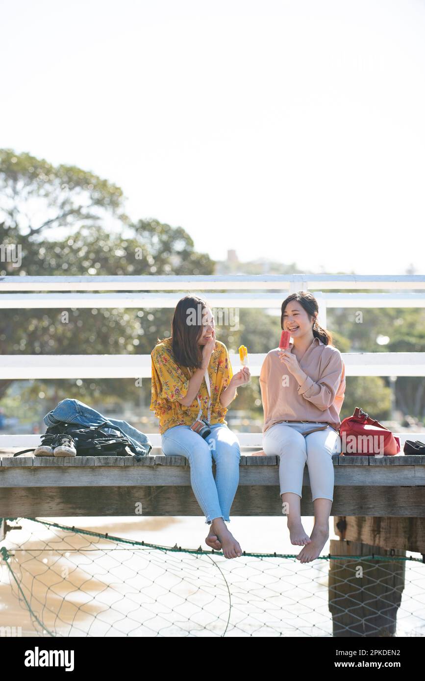 Two women laughing while eating ice cream Stock Photo - Alamy
