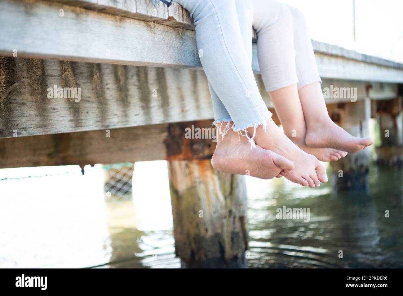 Feet of two women sitting on pier Stock Photo - Alamy