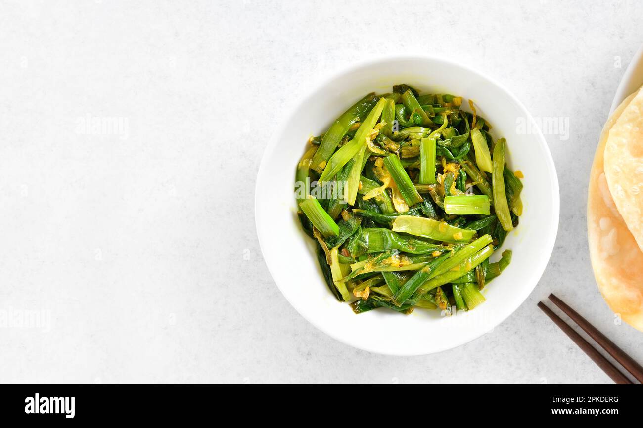 Indian style spring onion stir fry in bowl over white background with ...