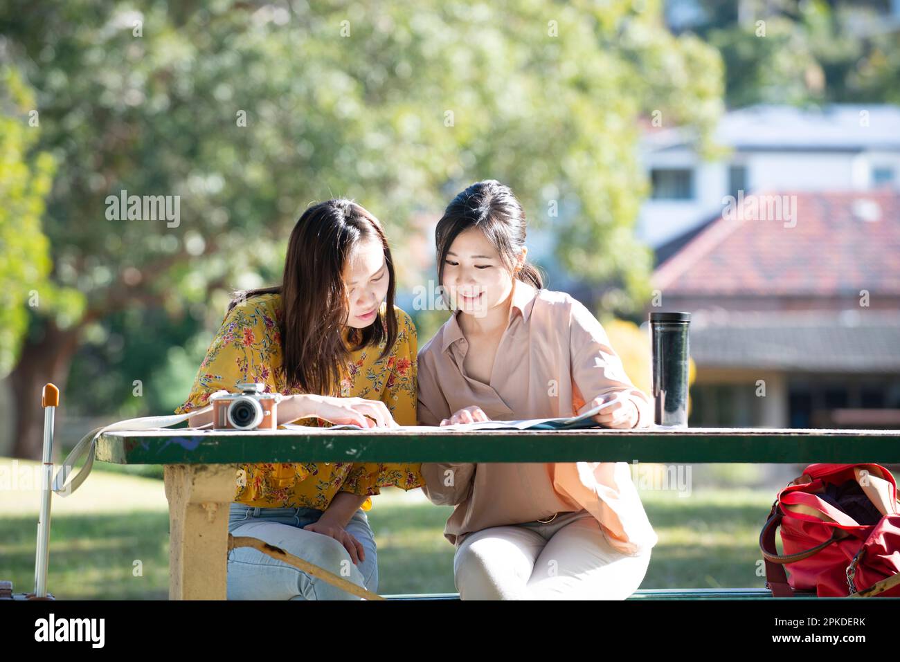 Two women planning a trip while looking at a map Stock Photo - Alamy
