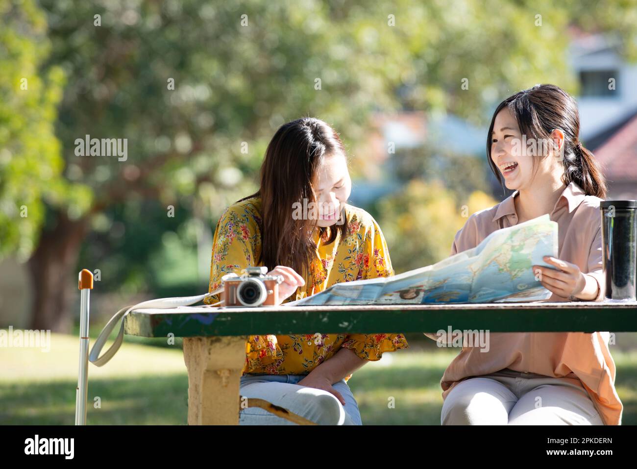 Two women planning a trip while looking at a map Stock Photo - Alamy