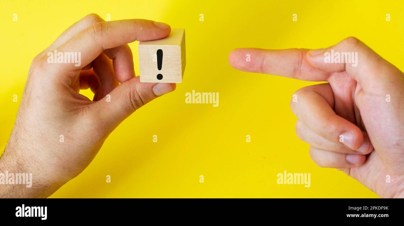 an exclamation mark drawn on a block of wood that a man holds in his ...