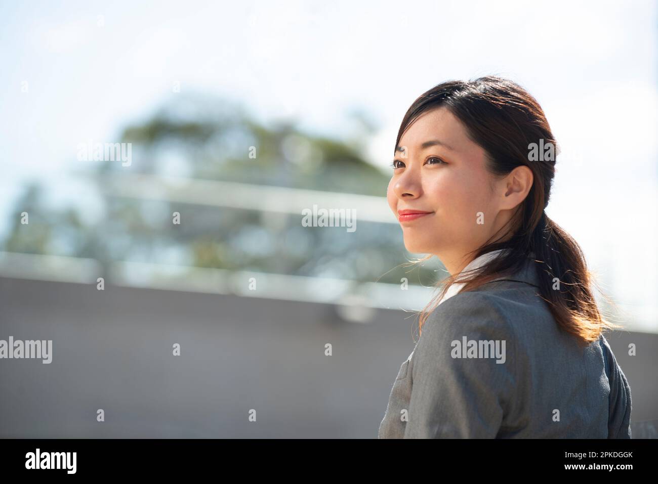 Woman in suit looking back and smiling Stock Photo - Alamy