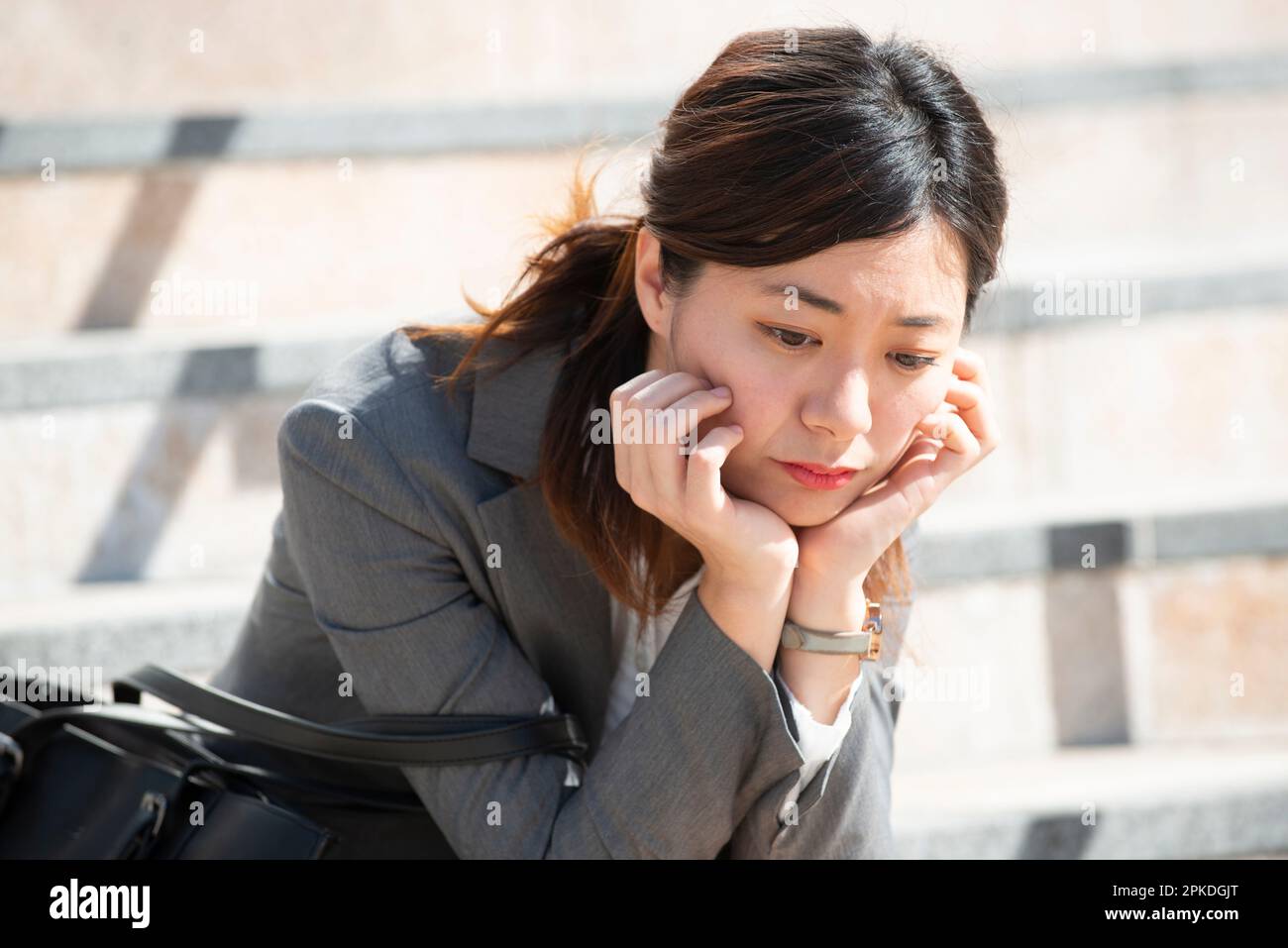 A woman in a suit sitting on the stairs thinking Stock Photo - Alamy