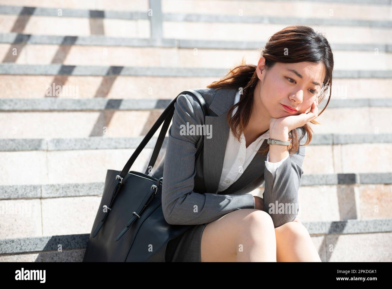 Woman in suit sitting on stairs thinking Stock Photo - Alamy