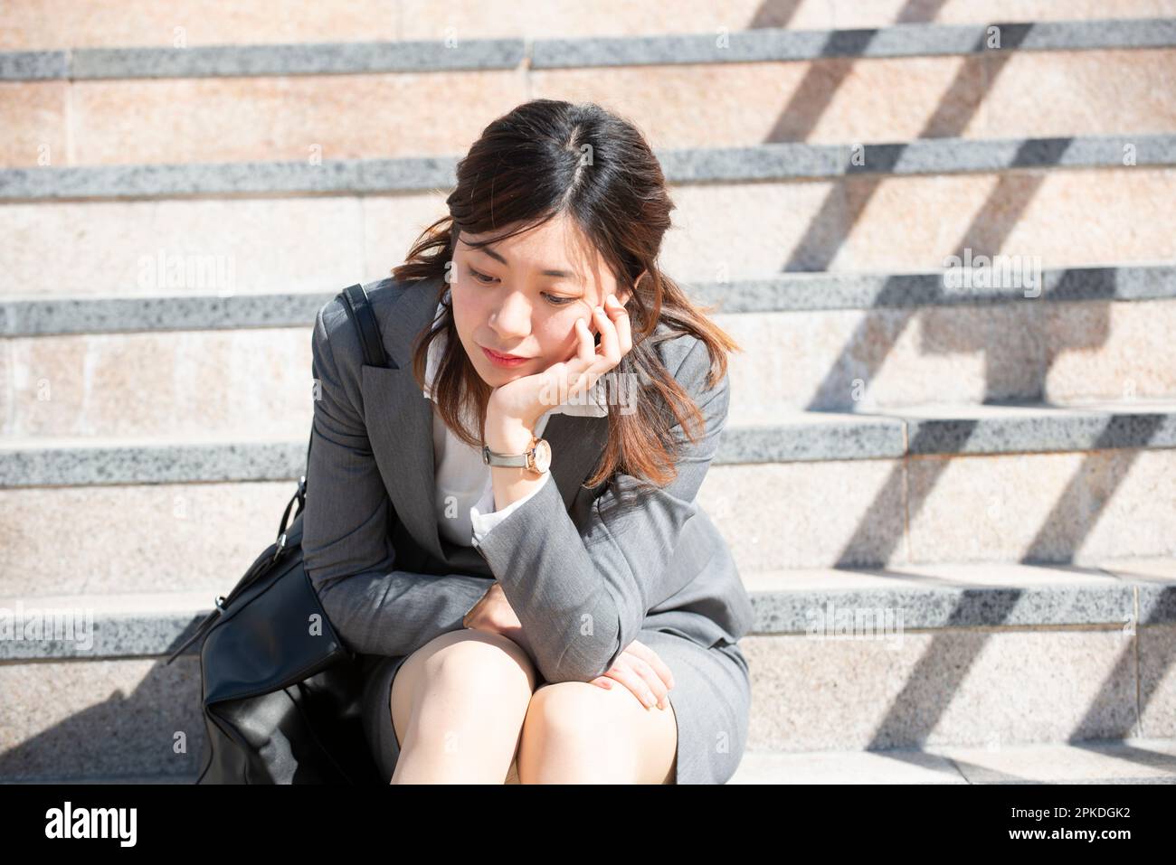 Woman in suit sitting on stairs thinking Stock Photo - Alamy