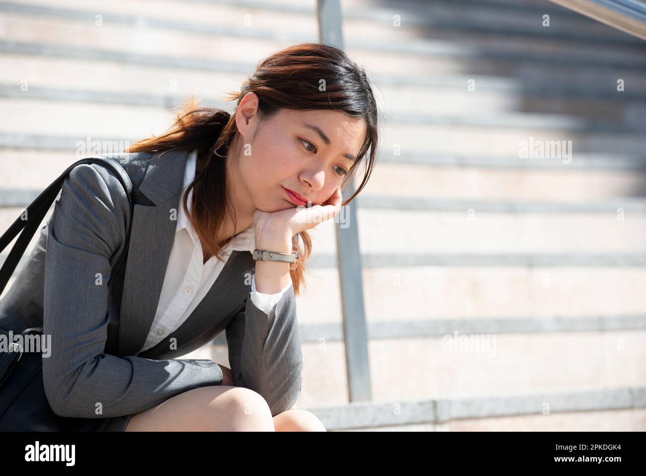 Woman in suit sitting on stairs thinking Stock Photo - Alamy