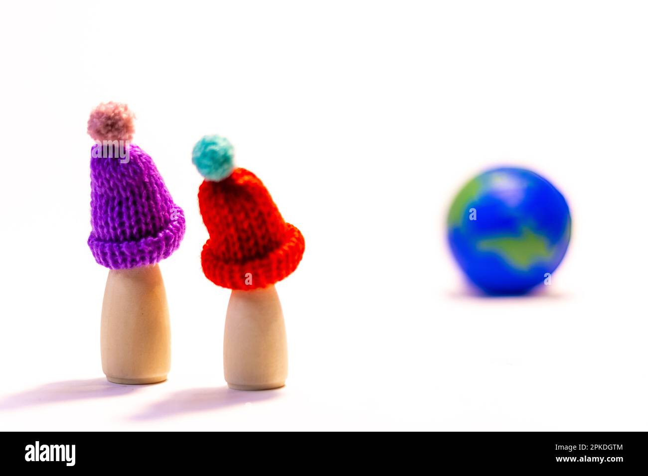 Two wooden figure people stand together as they look on at the planet ...