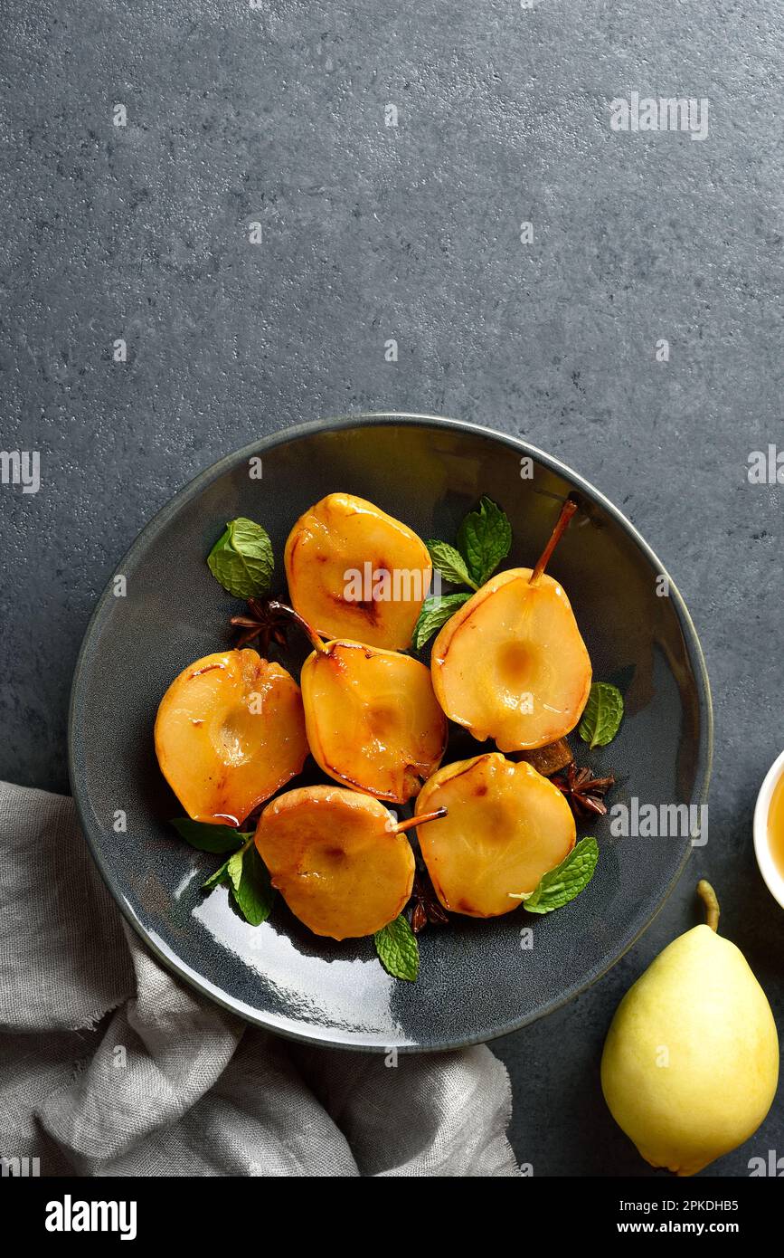 Poached pears on plate over dark stone background with copy space. Top ...