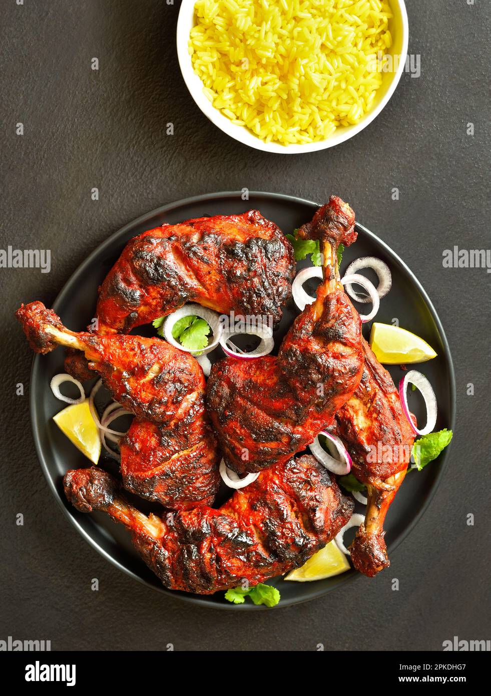 Indian style tandoori chicken on plate over dark stone background ...