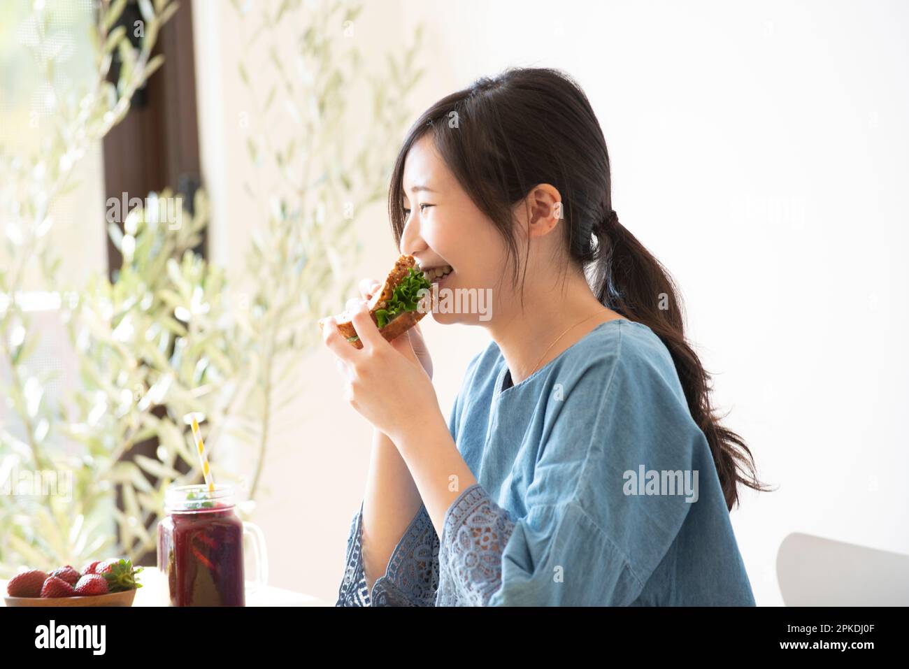 Woman laughing while eating a sandwich Stock Photo - Alamy