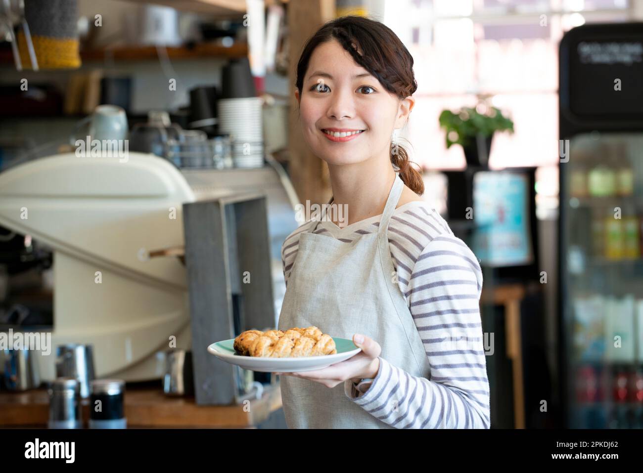 A smiling shopkeeper woman holding a loaf of bread Stock Photo - Alamy
