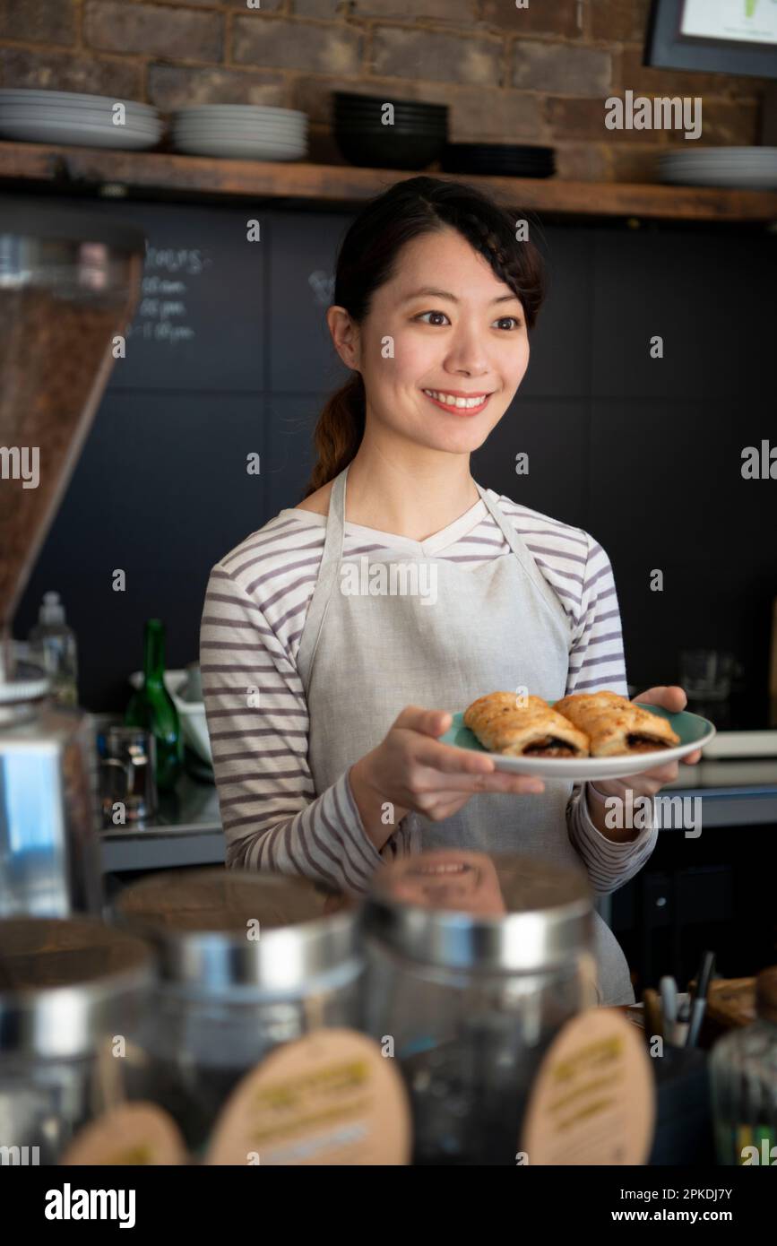 A smiling female waitress working in a café Stock Photo - Alamy