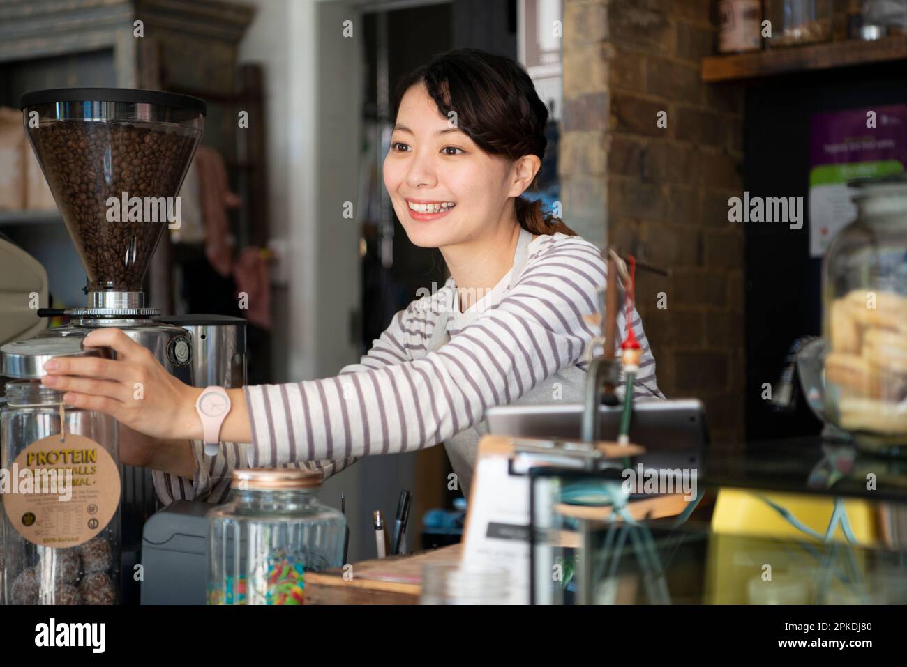 A smiling female waitress working in a café Stock Photo - Alamy