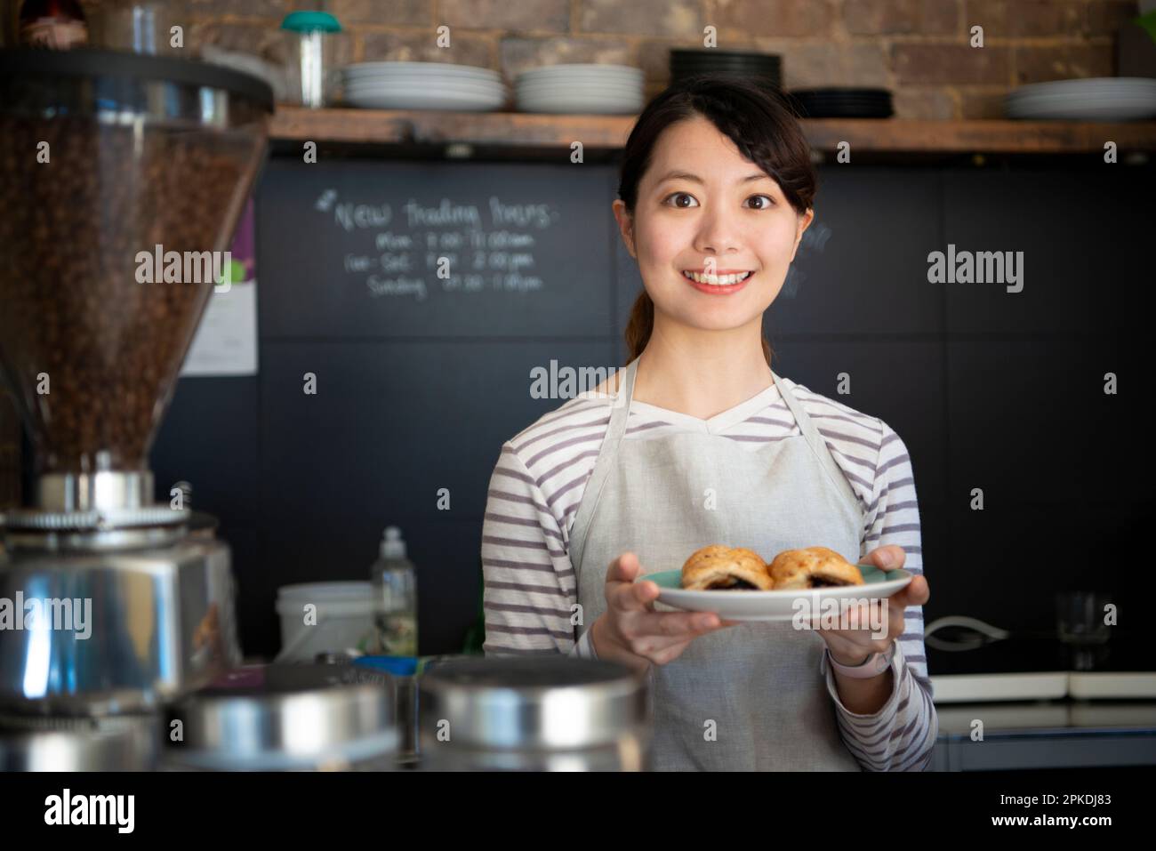 A smiling female waitress working in a café Stock Photo - Alamy