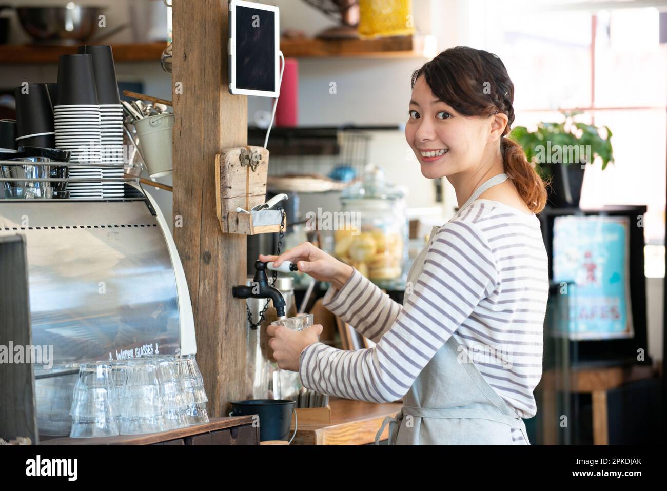 A smiling female waitress fetching water at a café Stock Photo - Alamy