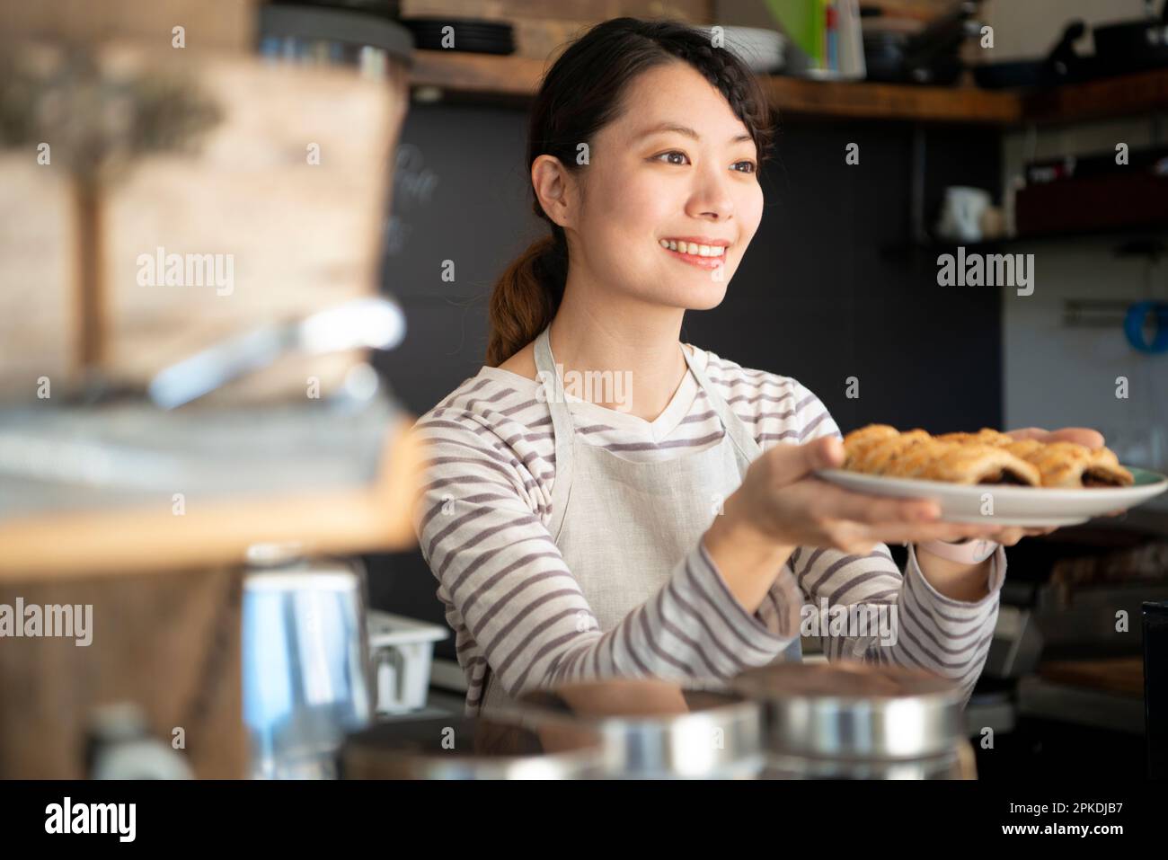 A smiling female waitress working at a café Stock Photo - Alamy