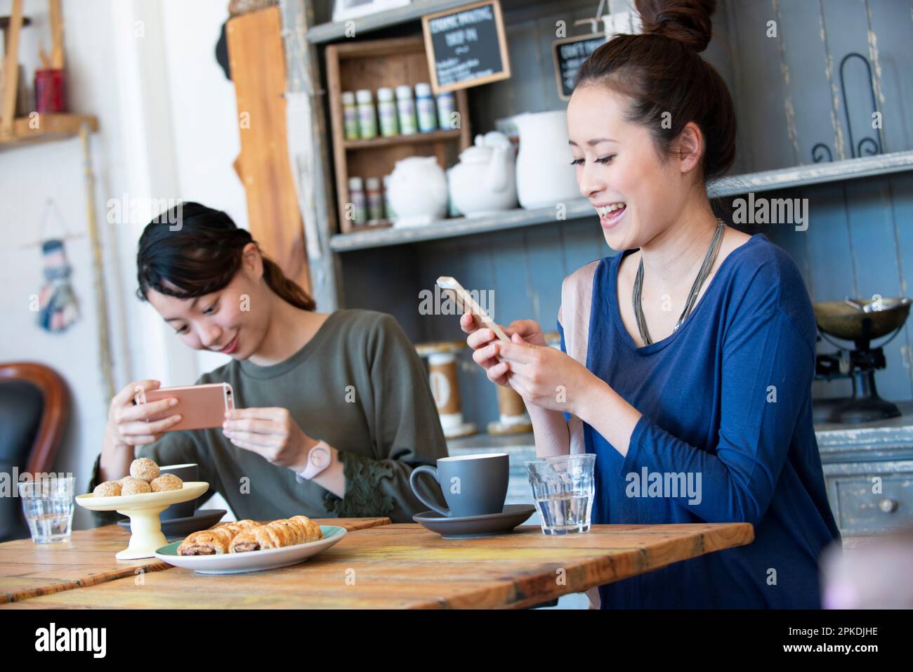 Women using their smartphones to take photos of sweets at a café Stock ...