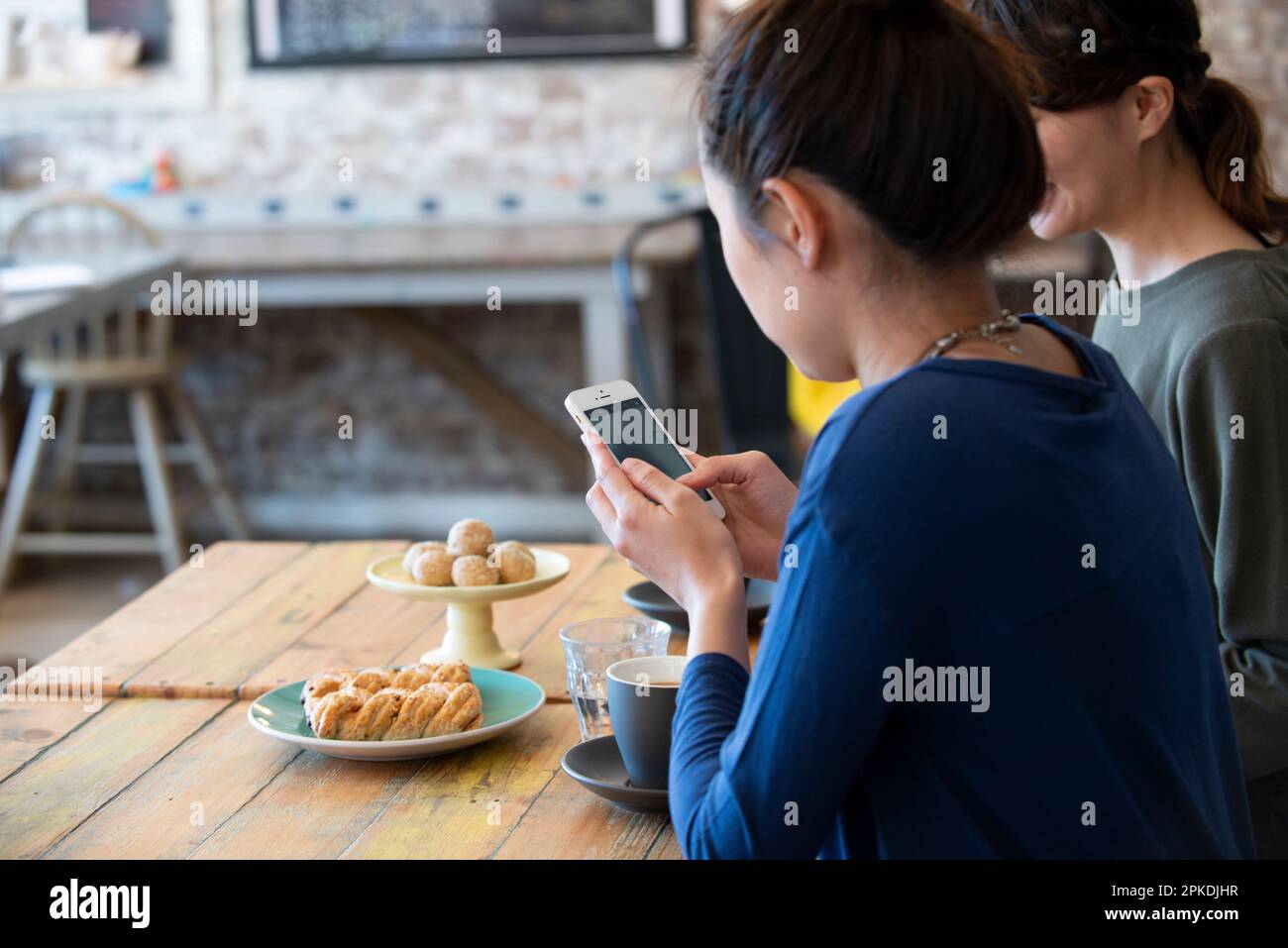 Woman taking a picture of sweets using her smartphone at a café Stock ...