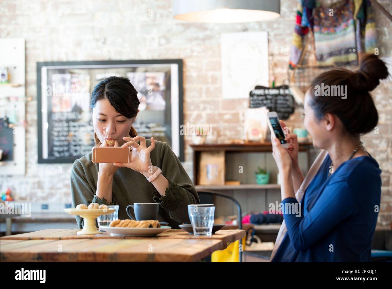 Women taking pictures of sweets using their smartphones at a café Stock ...