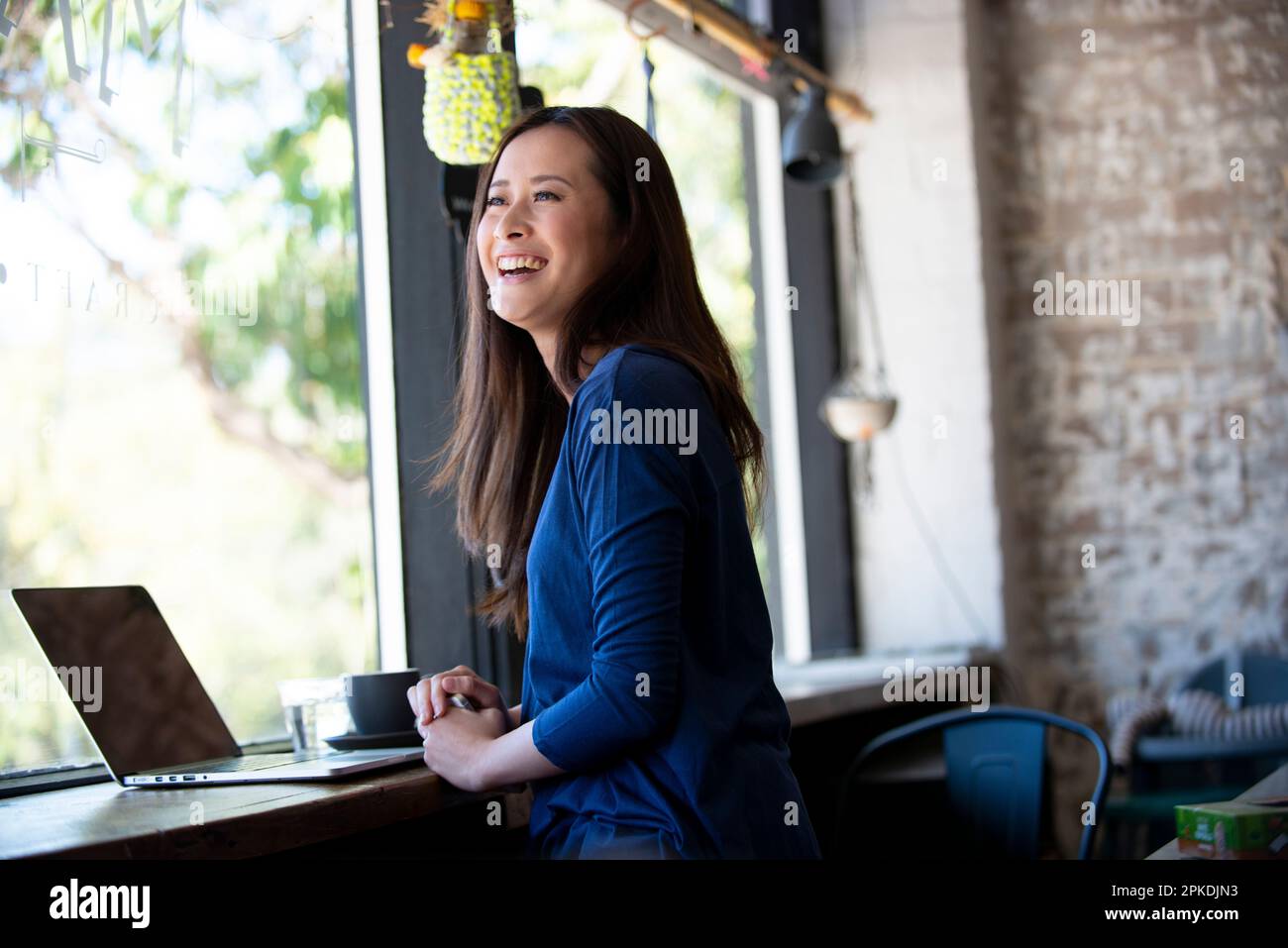 Woman laughing in front of a computer at a café Stock Photo - Alamy