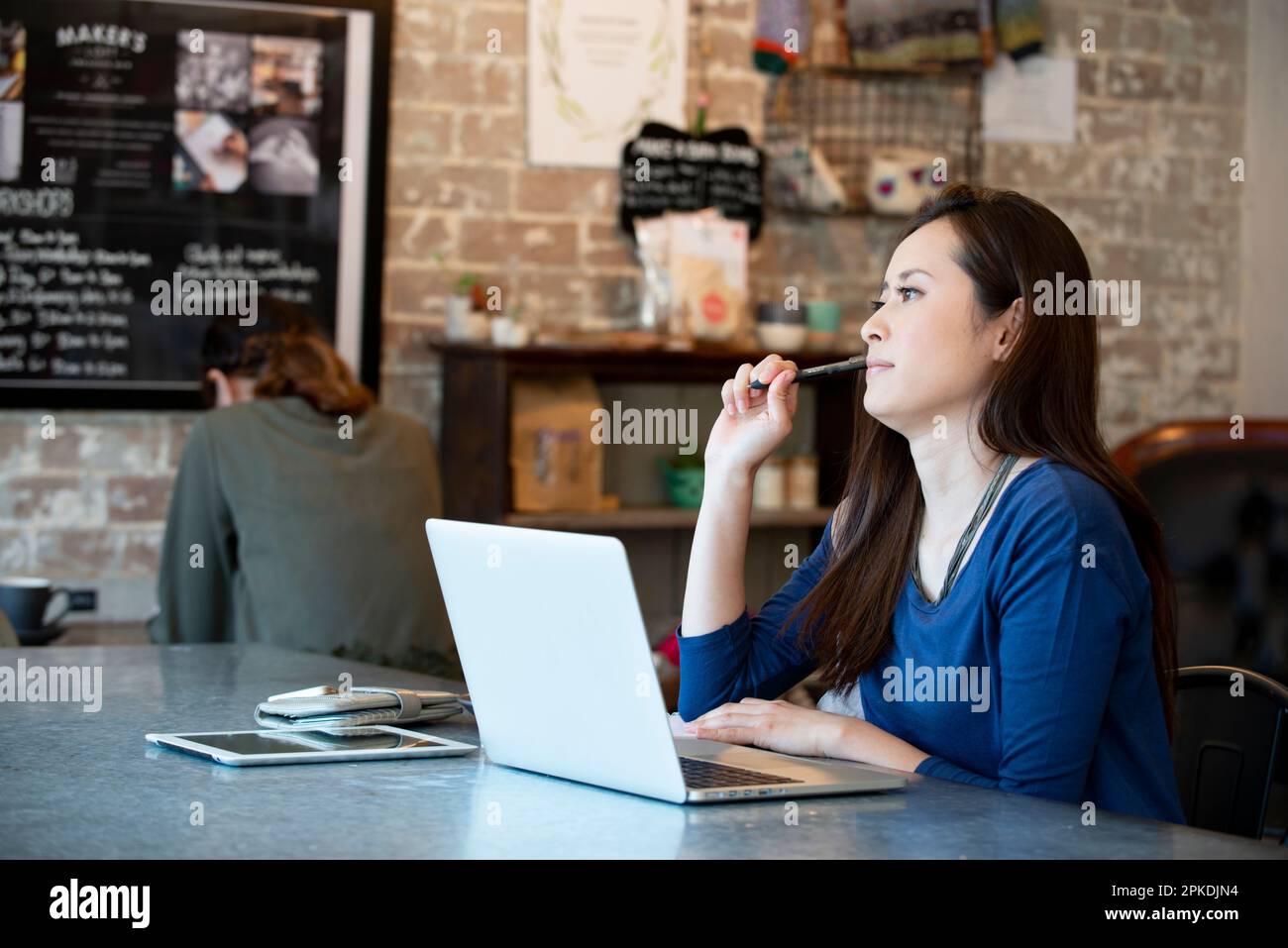 Woman thinking in front of a computer at a café Stock Photo - Alamy
