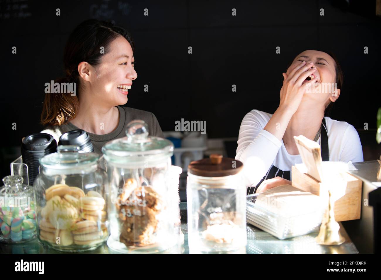 Two female waitresses laughing at the café Stock Photo - Alamy