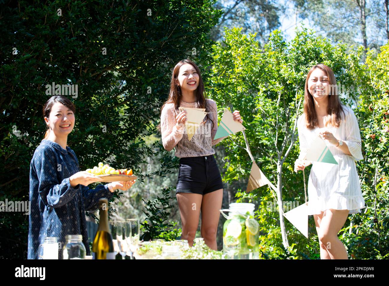 Three smiling women preparing for a garden party Stock Photo - Alamy