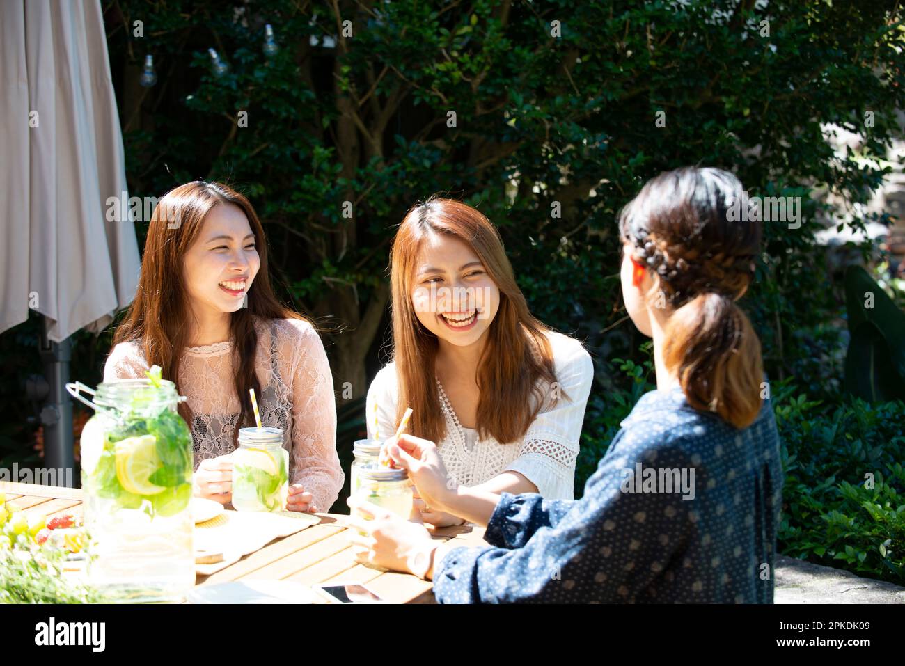 Three women smiling and talking at a garden party Stock Photo - Alamy