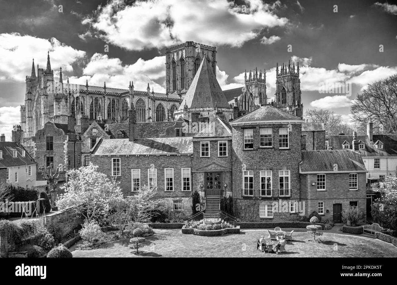 York Minster looms above a large brick building with tables and chairs ...