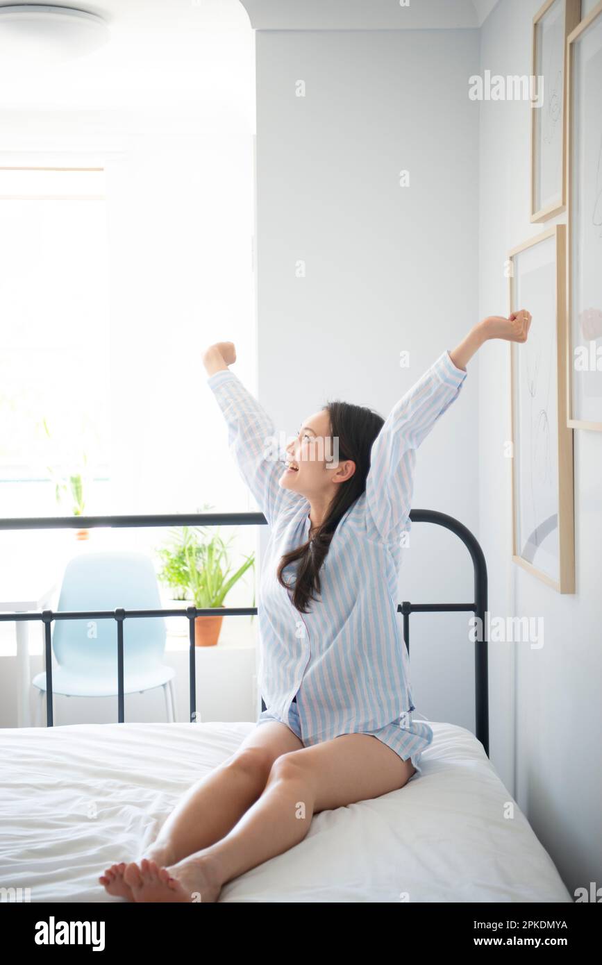 Woman in pajamas stretching on bed Stock Photo - Alamy