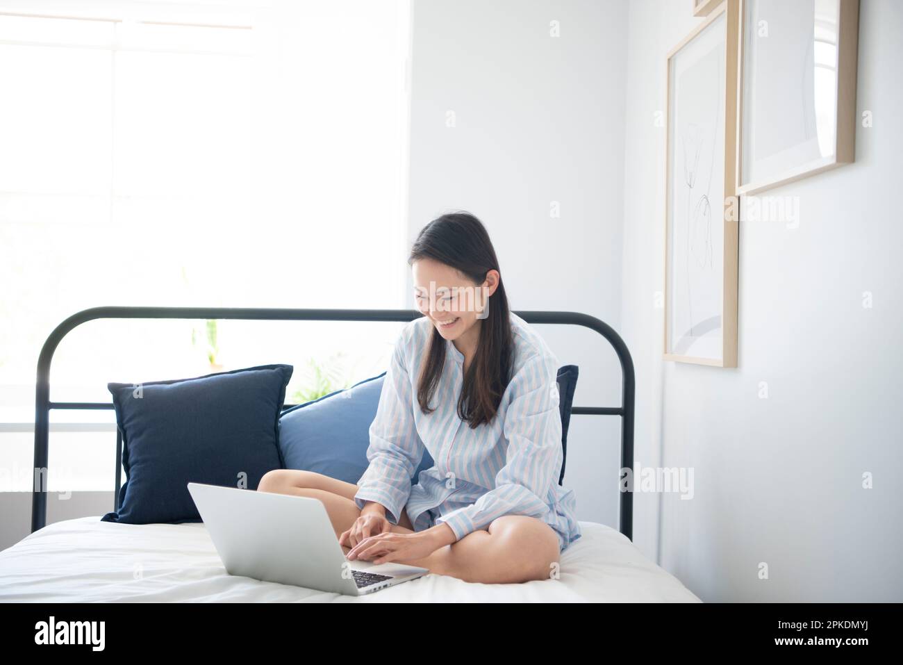 Woman in pajamas touching computer on bed Stock Photo - Alamy