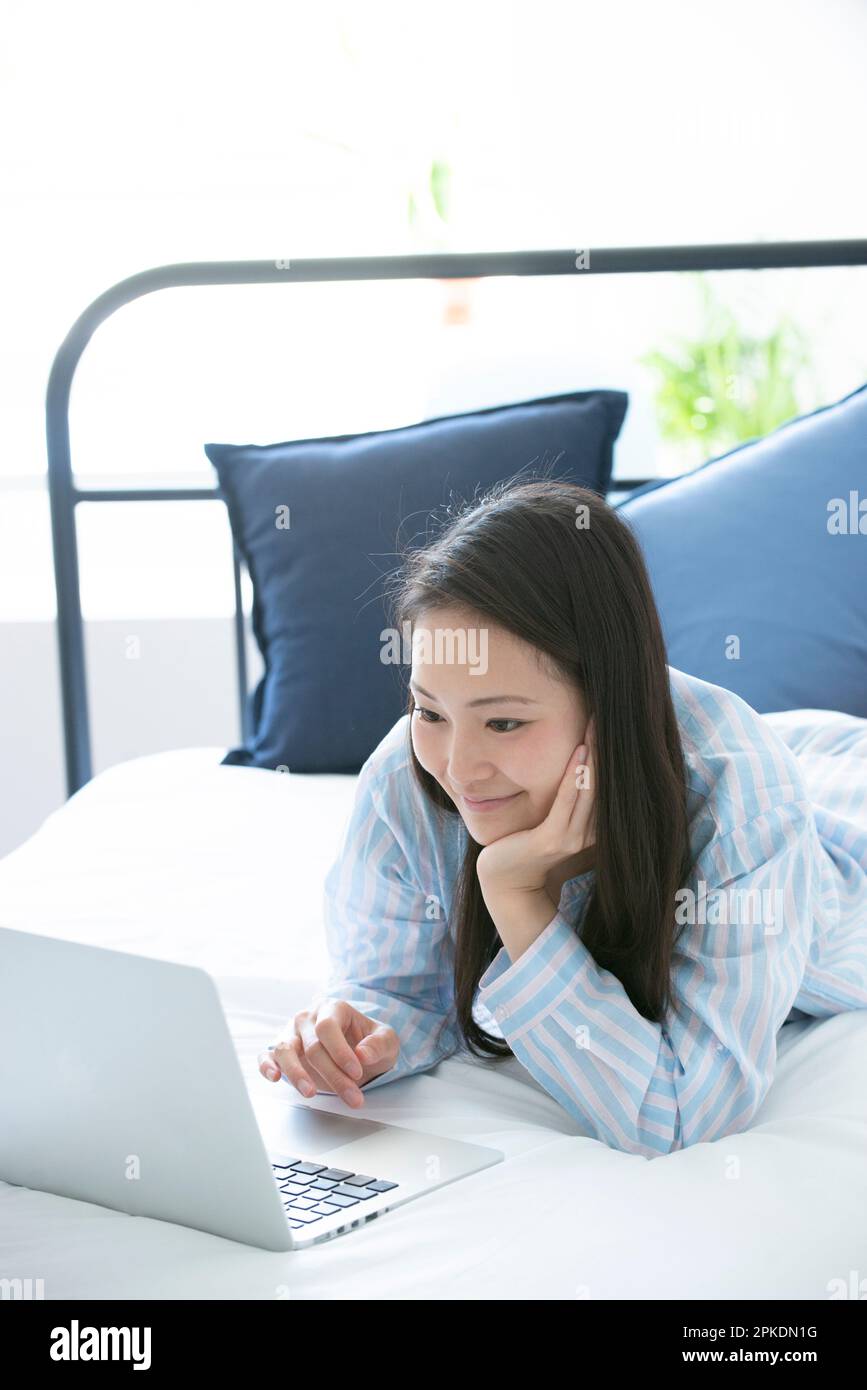 Woman in pajamas touching computer on bed Stock Photo - Alamy
