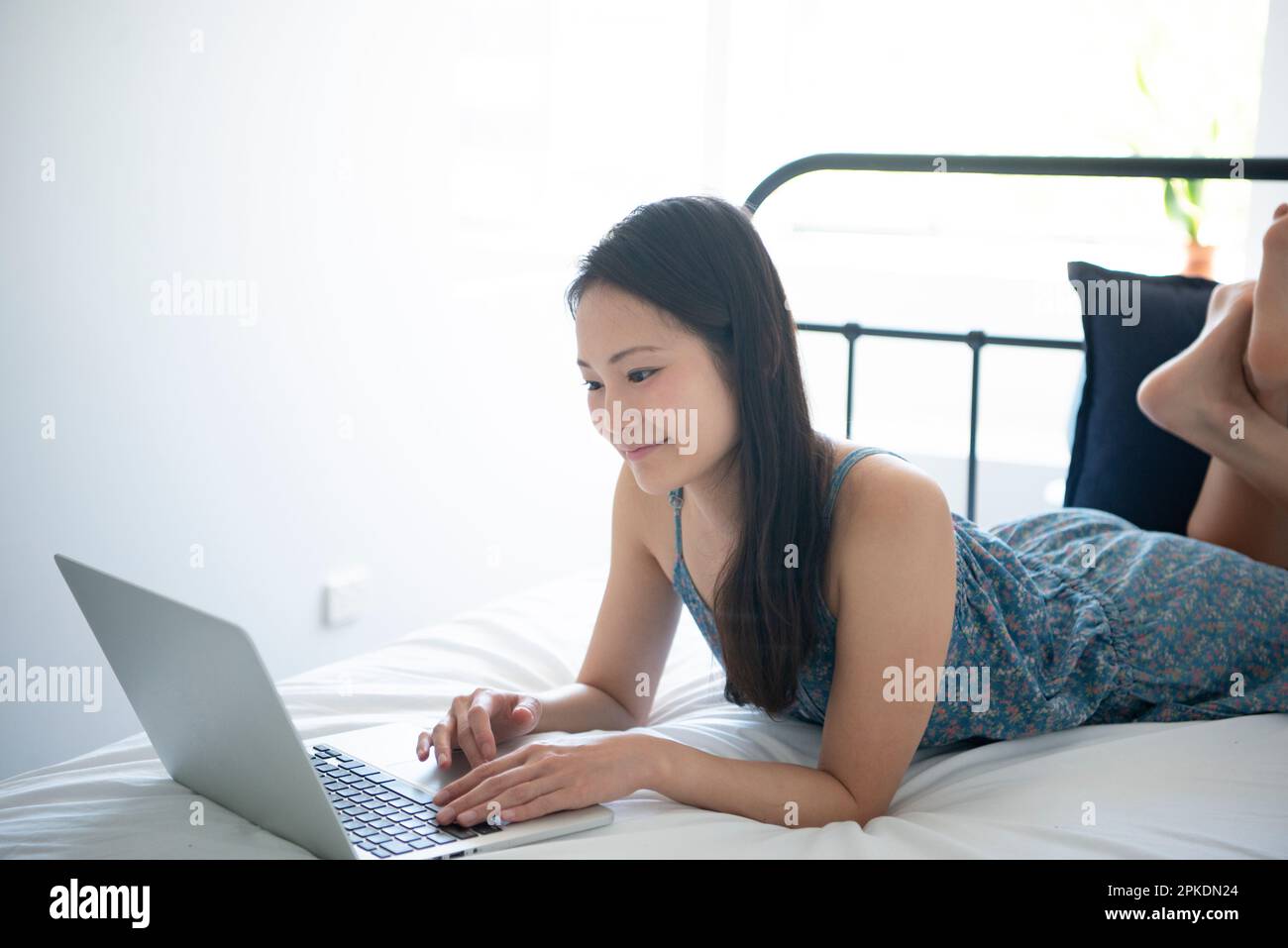 Woman lying on bed touching computer Stock Photo - Alamy