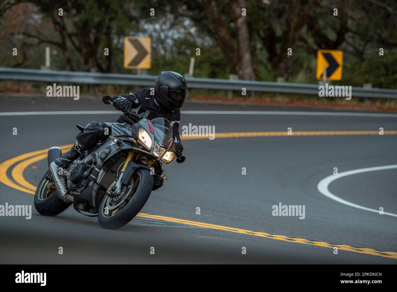 A person riding a motorcycle down a winding road Stock Photo - Alamy