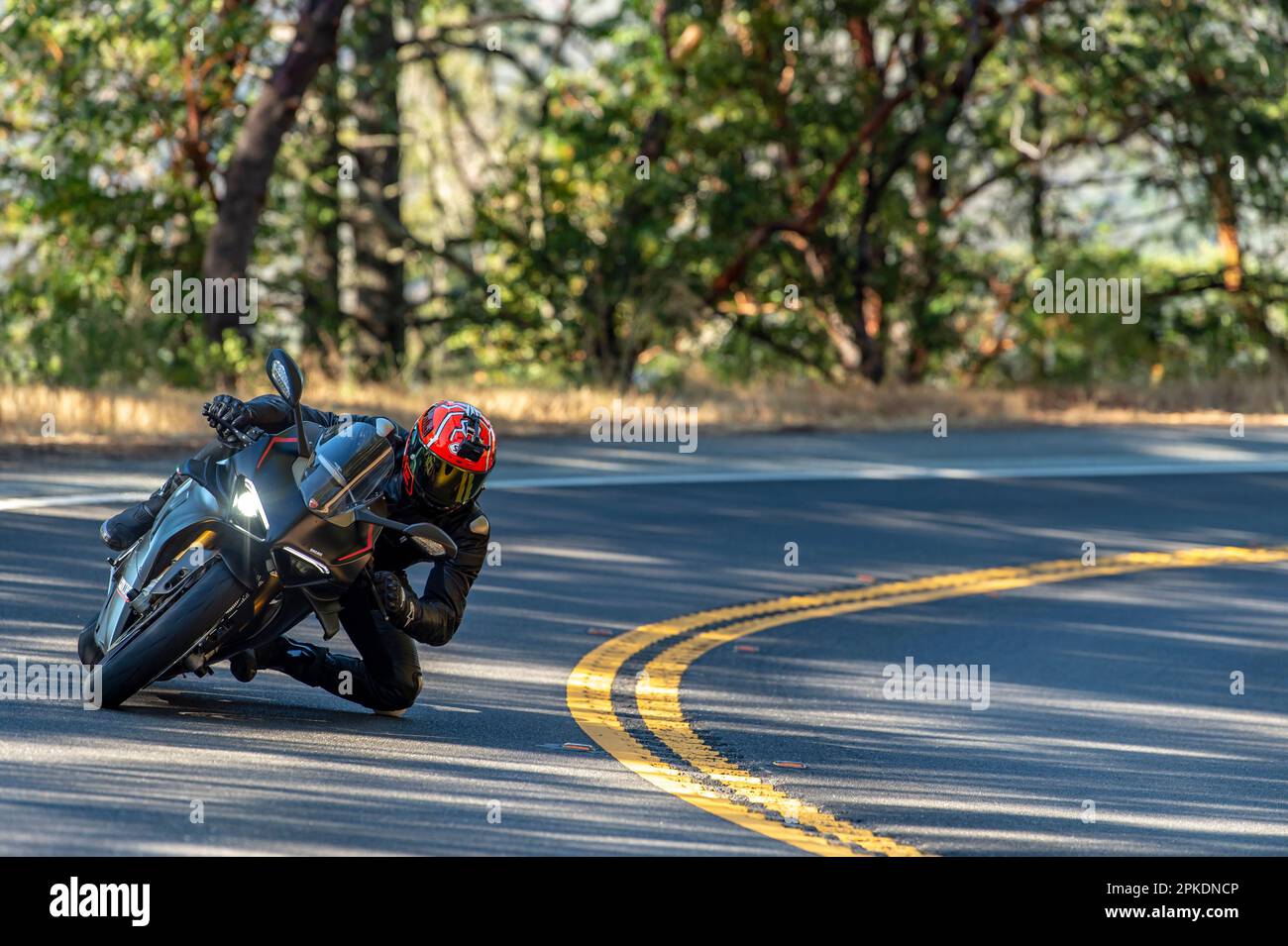 A person riding a motorcycle down a winding road Stock Photo - Alamy