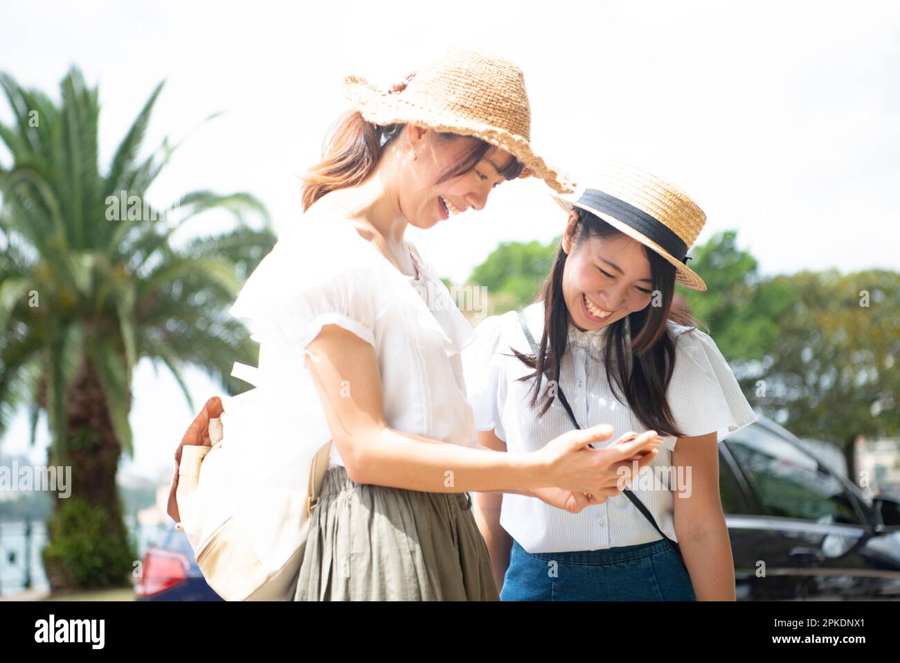 Two women laughing while looking at their phones Stock Photo - Alamy