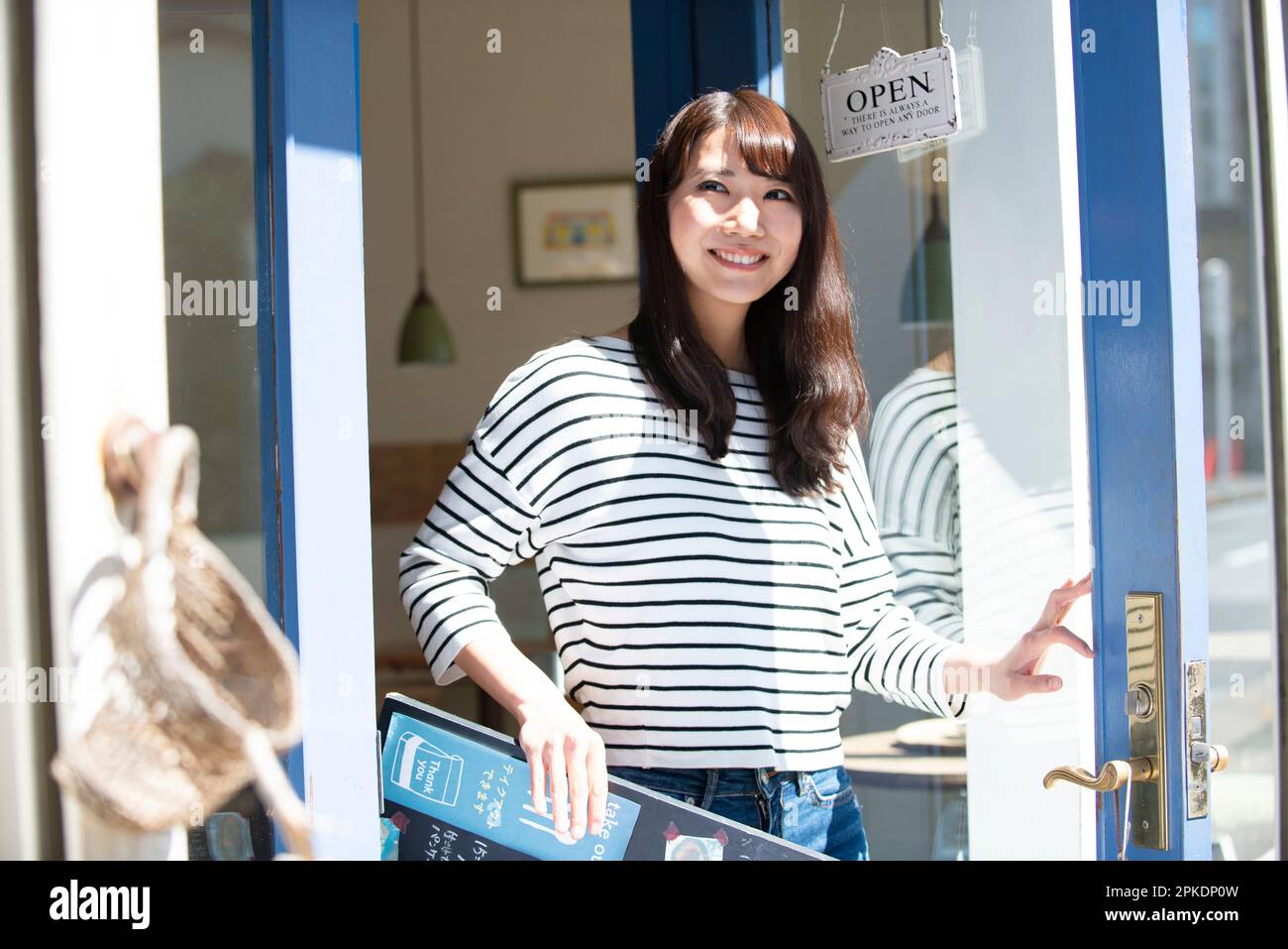 Woman laughing in front of a store holding a sign Stock Photo - Alamy