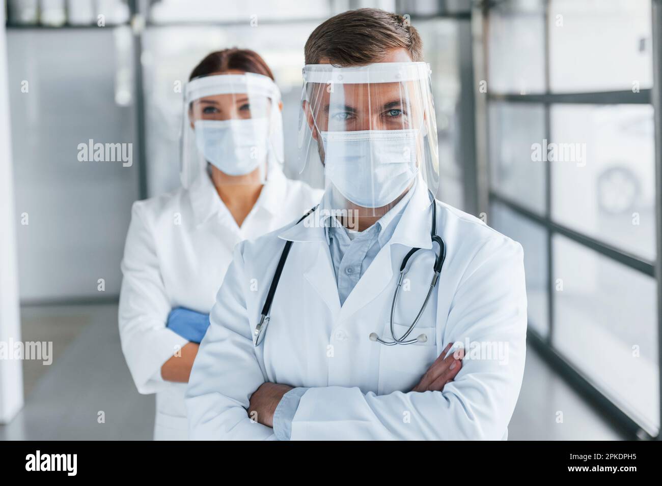 Standing with arms crossed. Two doctors in white coats is in the clinic ...