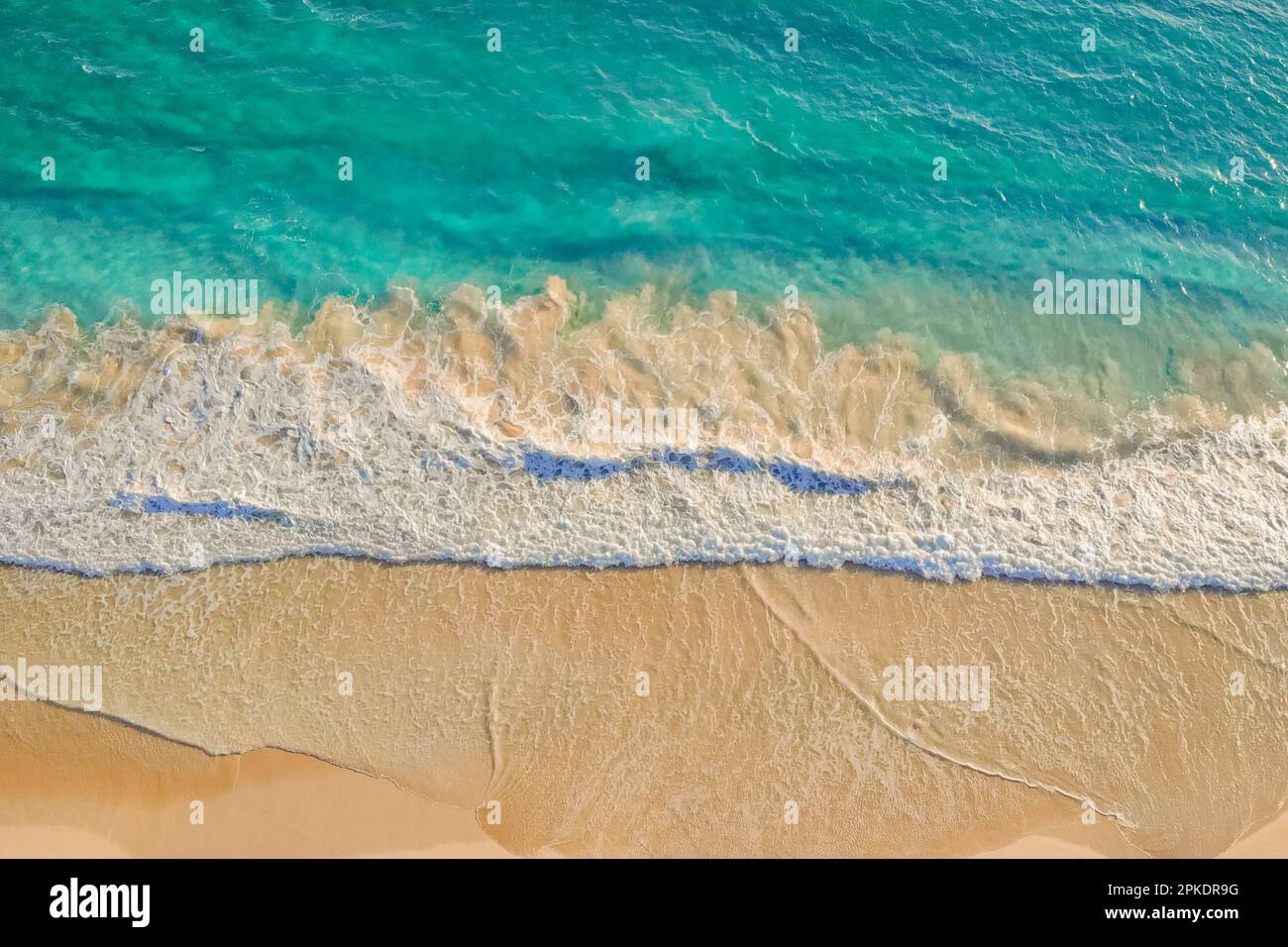 TOP VIEW: Aerial view of turquoise ocean wave reaching coastline ...
