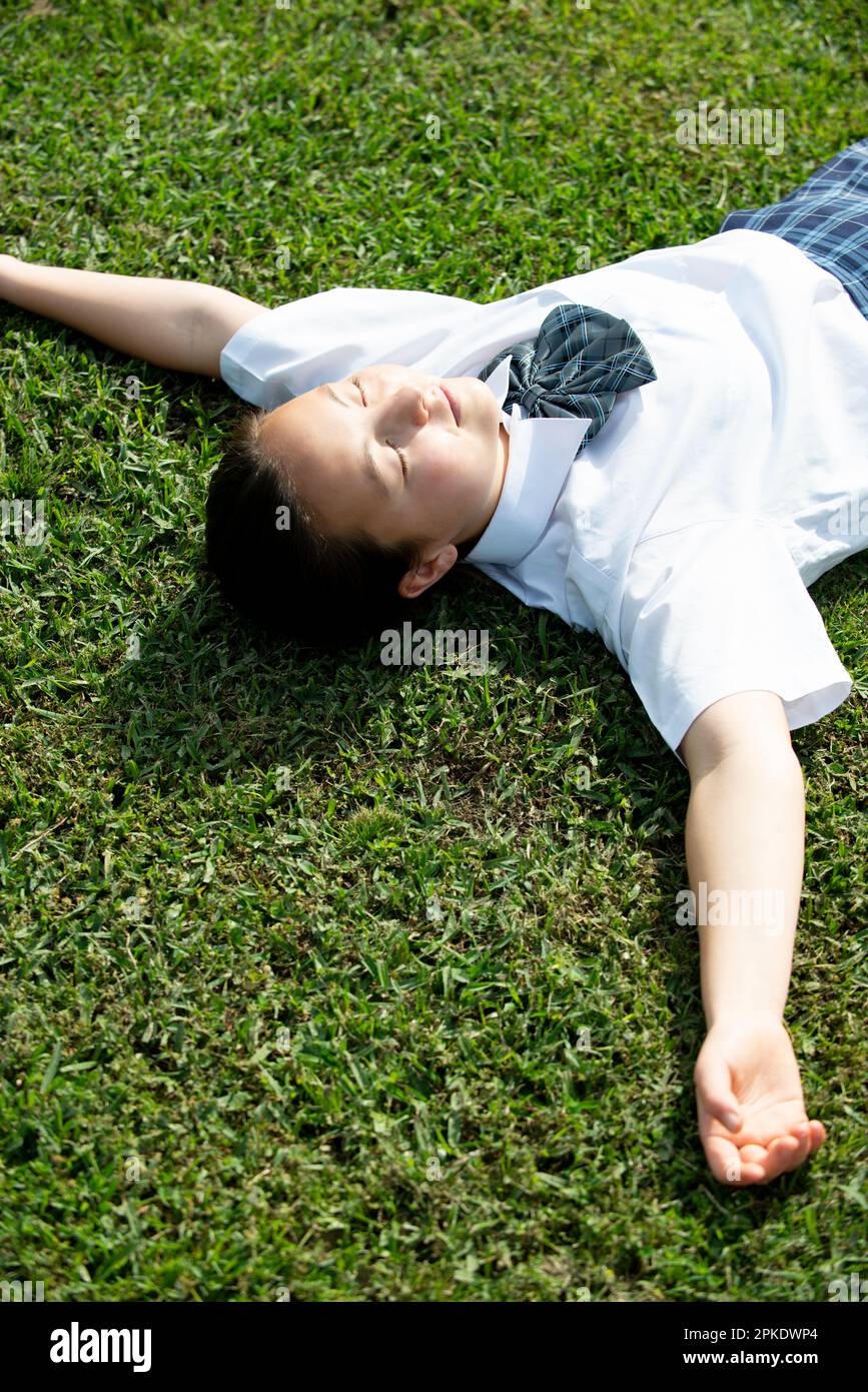 Schoolgirl in school uniform lying on the grass Stock Photo - Alamy